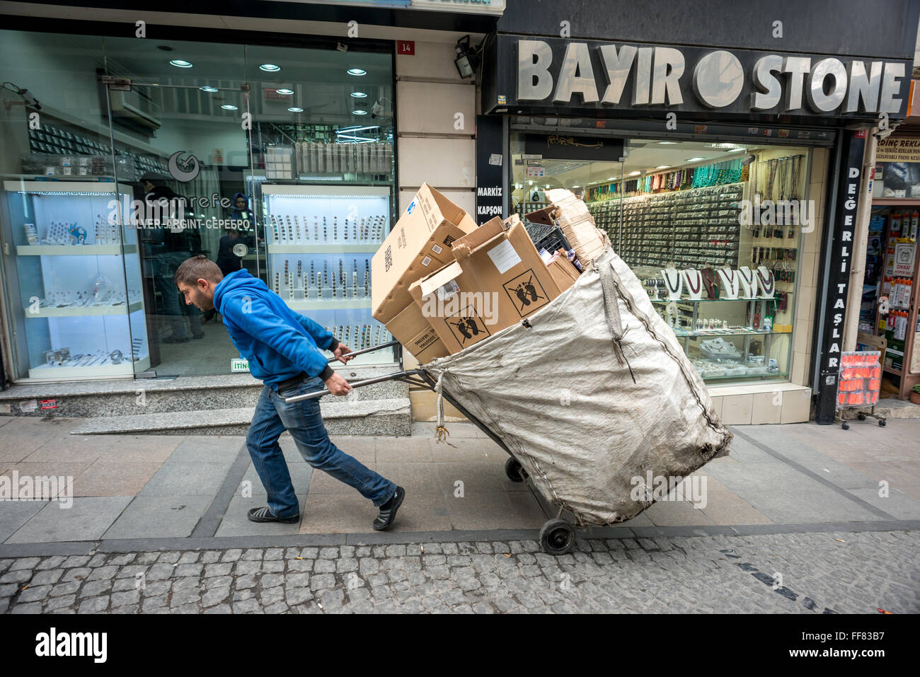 A young man pulling a trolley filled with cardboard for recycling ...