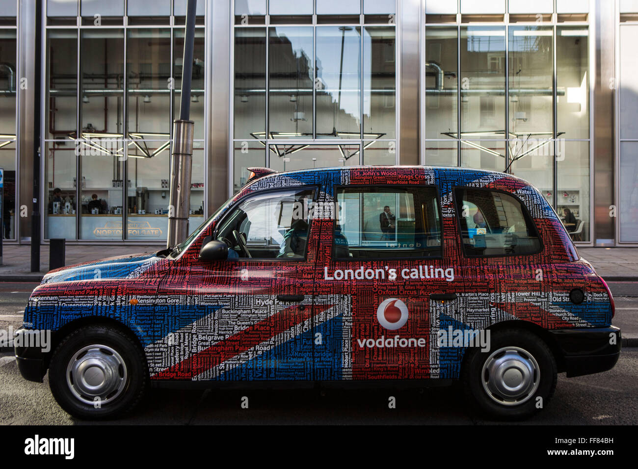 A traditional London Hackney carriage taxi cab advertising Vodafone, a ...