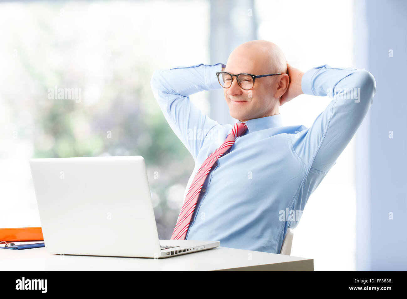 Portrait of confident businessman sitting at desk while relaxing at ...