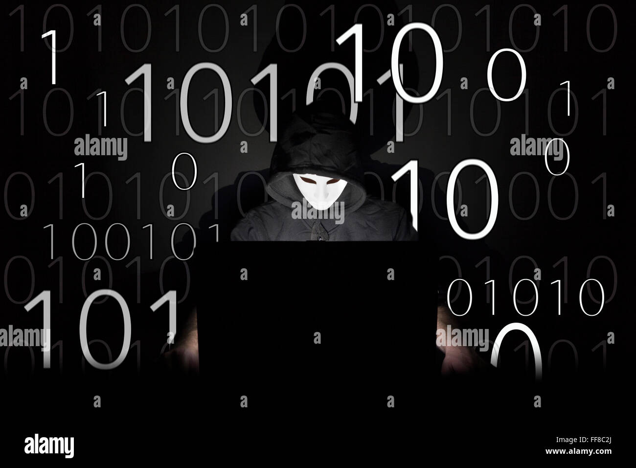 A masked man at a laptop symbolising the dangers of the Internet Stock ...