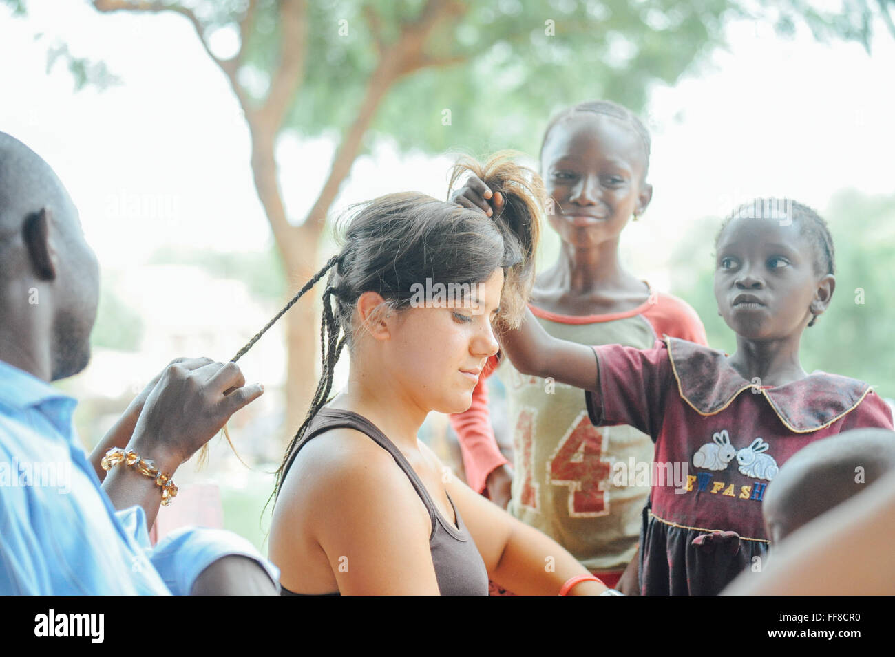 Young caucasian volunteer woman having her hair coiffed by black ...