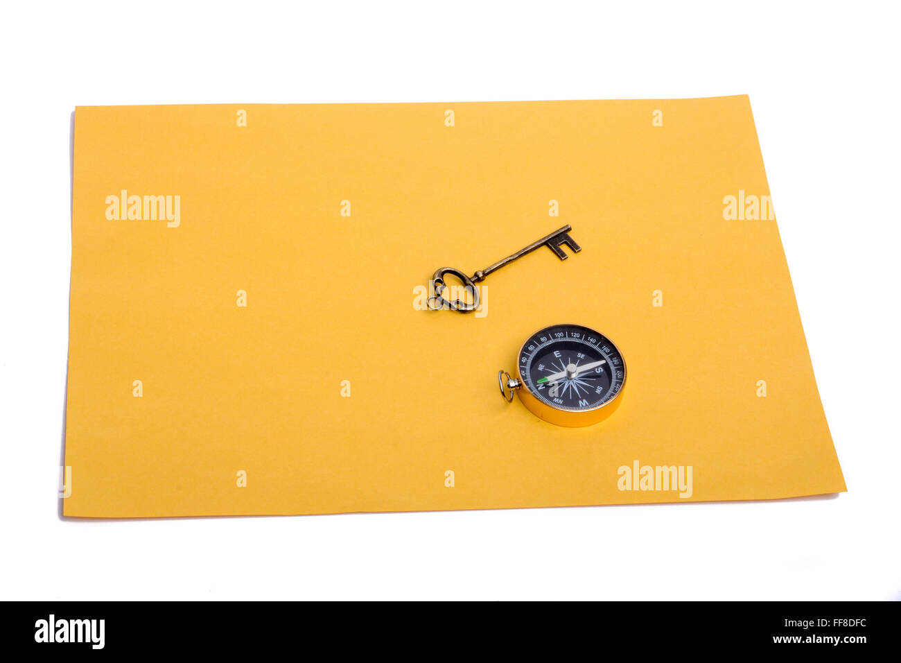 key and compass on a sheet of colored plain paper with a white ...