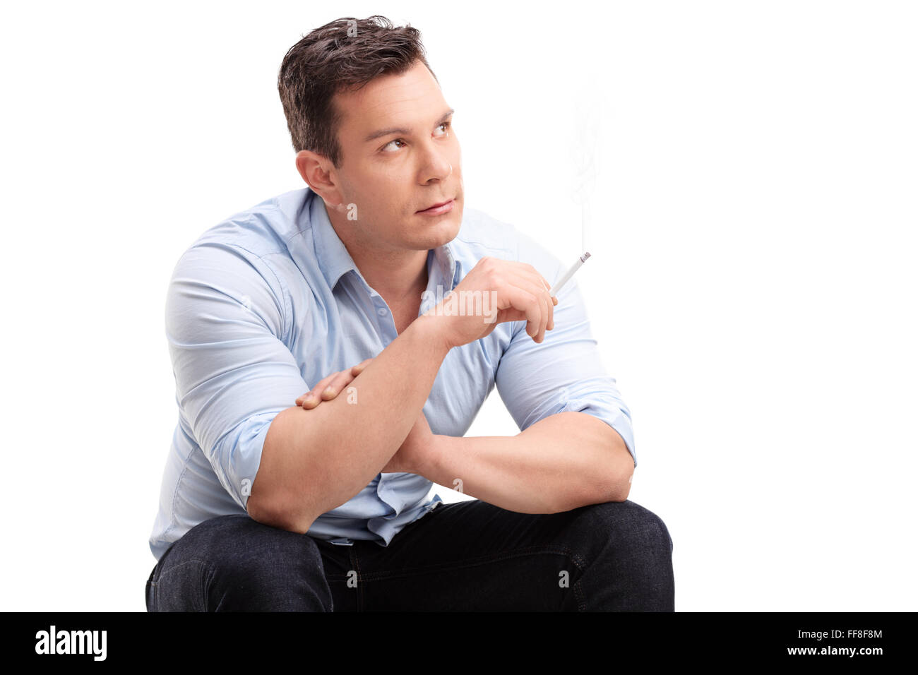 Pensive young man smoking a cigarette and looking up isolated on white ...