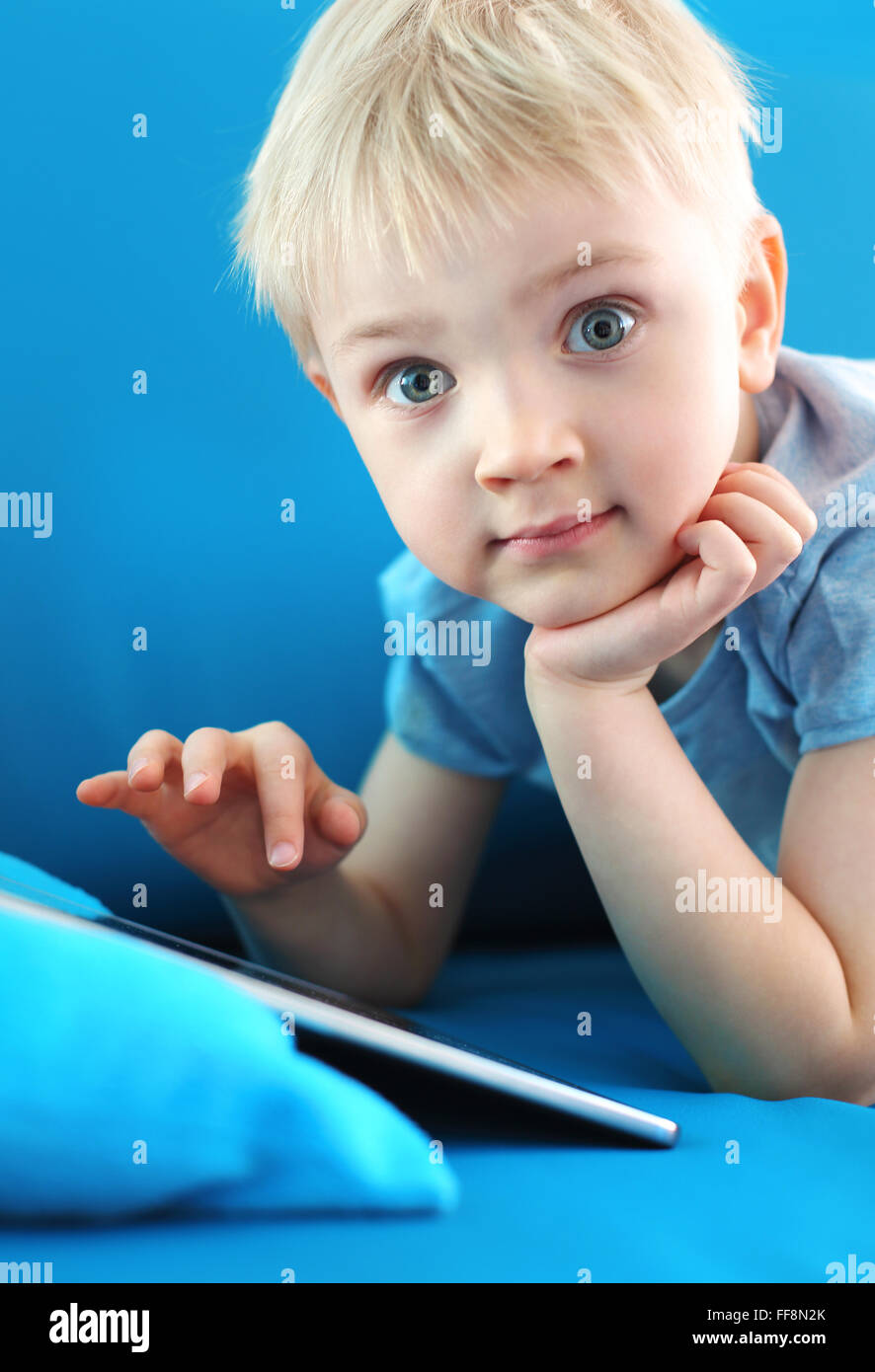 Small child and tablet. Child playing online games. Smiling boy and ...
