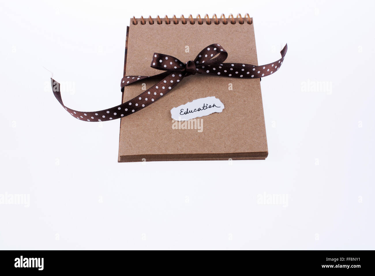 Spiral notebook with a ribbon and poll point pen and key on a white ...