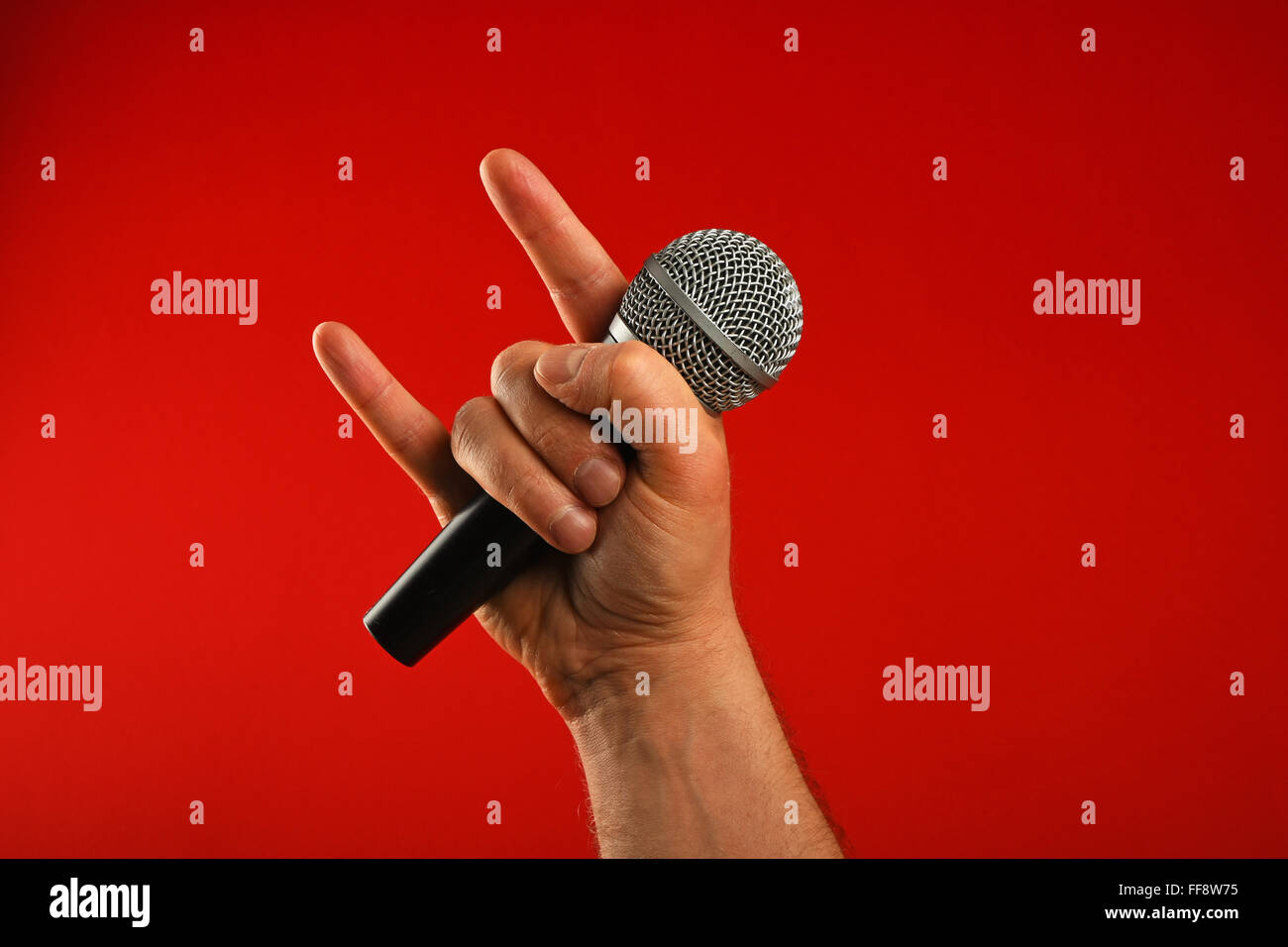 Man hand holding voice microphone with devil horns rock metal gesture ...