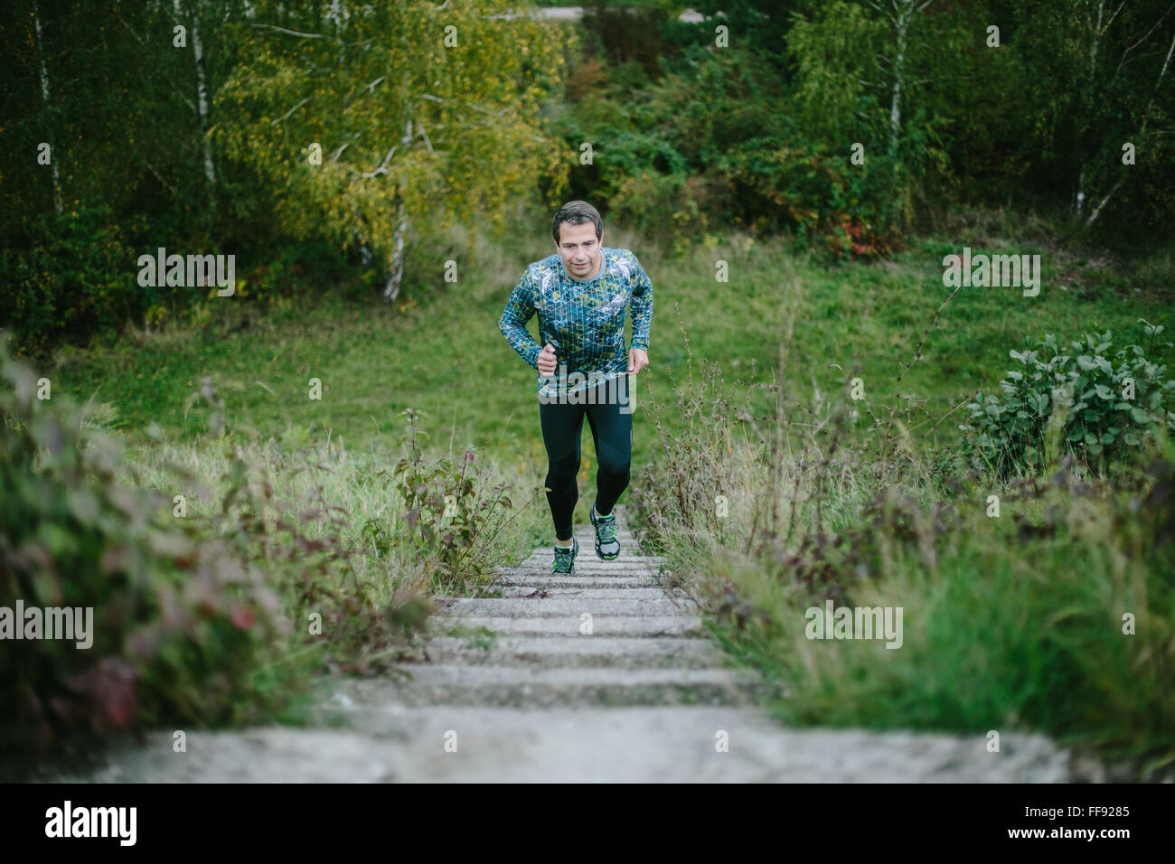 Man running up on stairs against green nature Stock Photo - Alamy