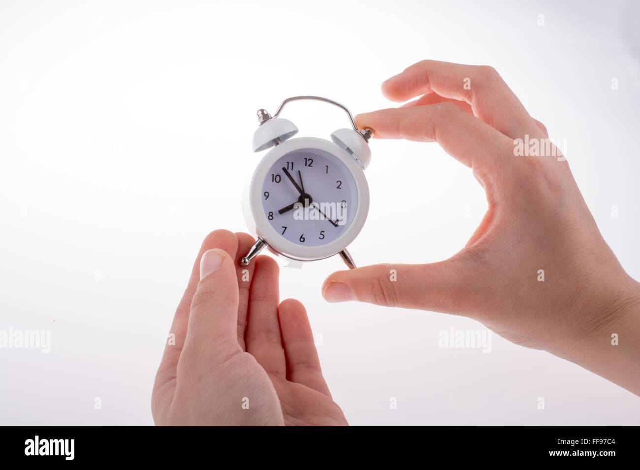 Alarm clock in hand on a white background Stock Photo - Alamy