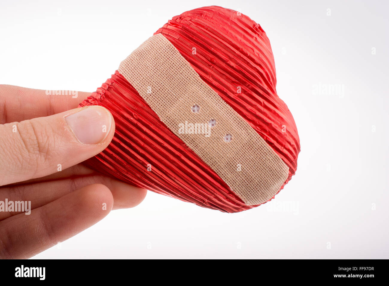 Hand holding a hurt heart with plaster in hand on white background ...