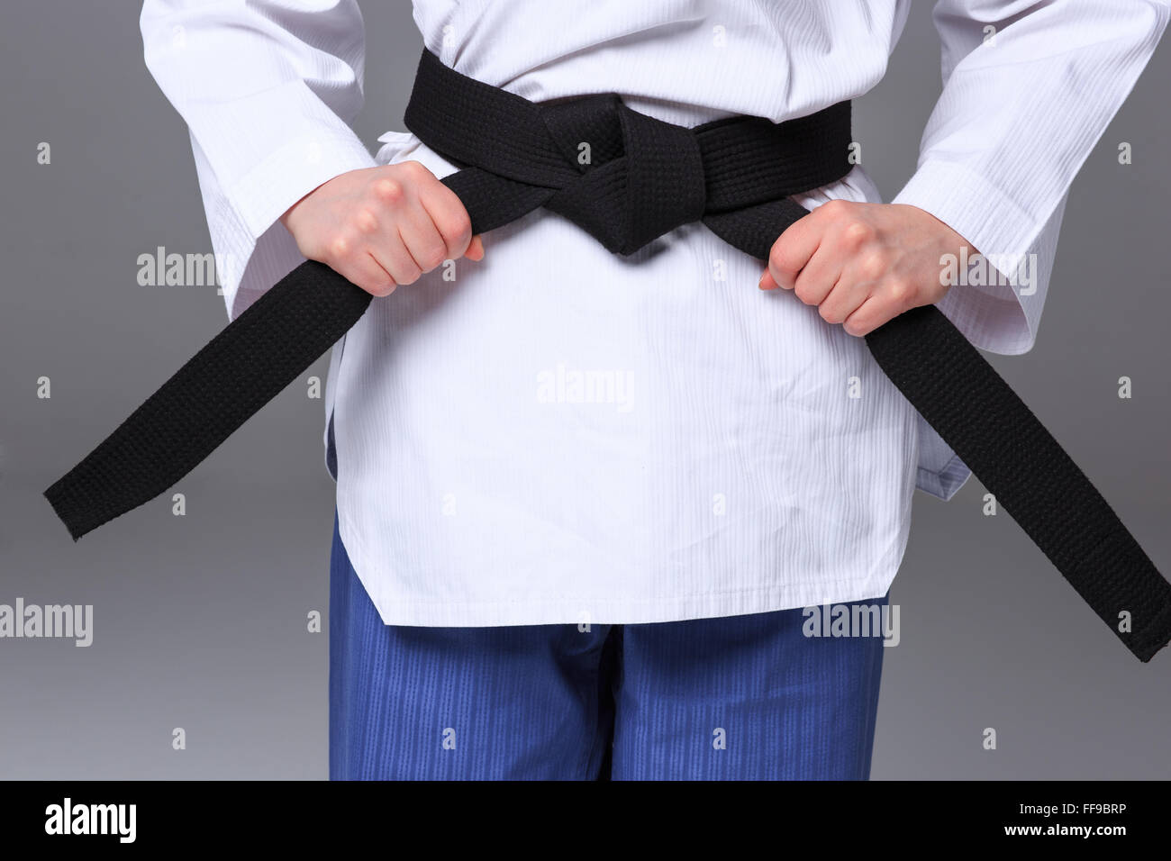 The hands of karate girl in white kimono and black belt training karate ...