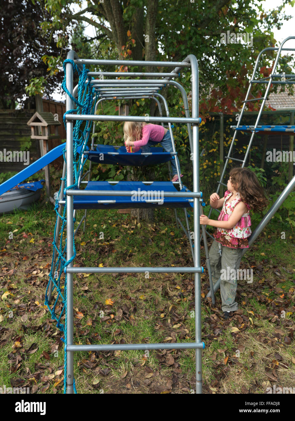 Two Girls Sisters On Climbing Frame In Garden England Stock Photo - Alamy