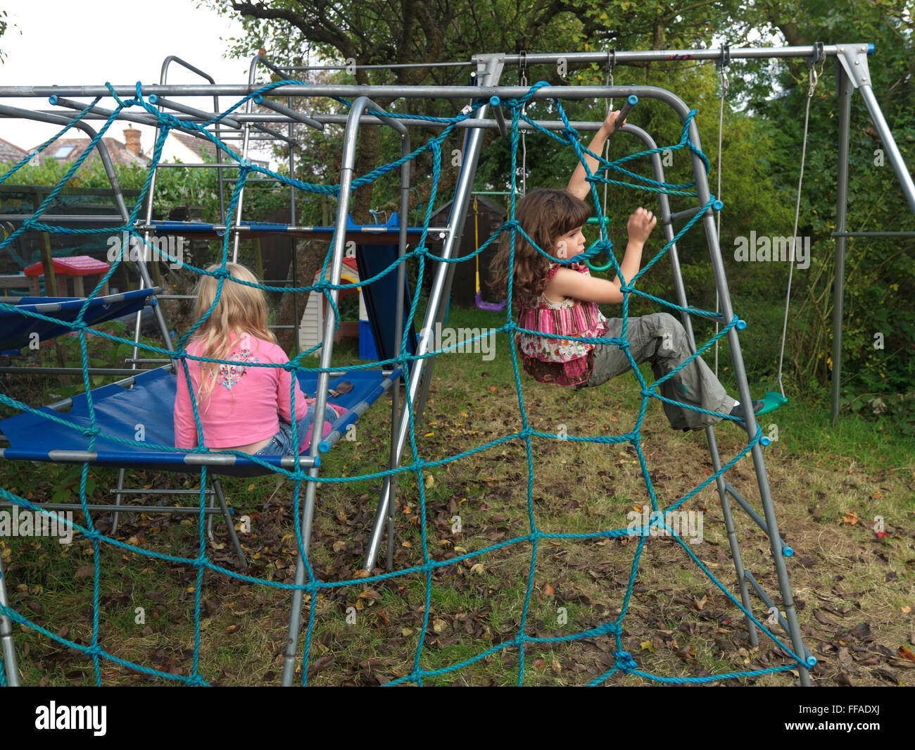 Two Girls Sisters On Climbing Frame In Garden England Stock Photo - Alamy