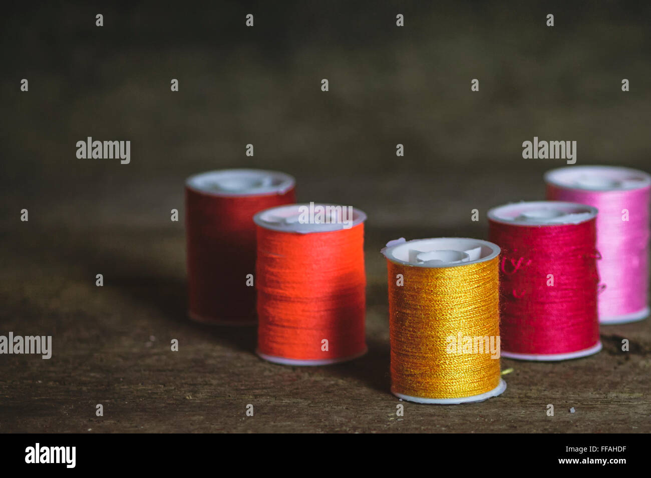 Set of Five Orange, Red and Pink Sewing Spools on Wood Background Stock ...