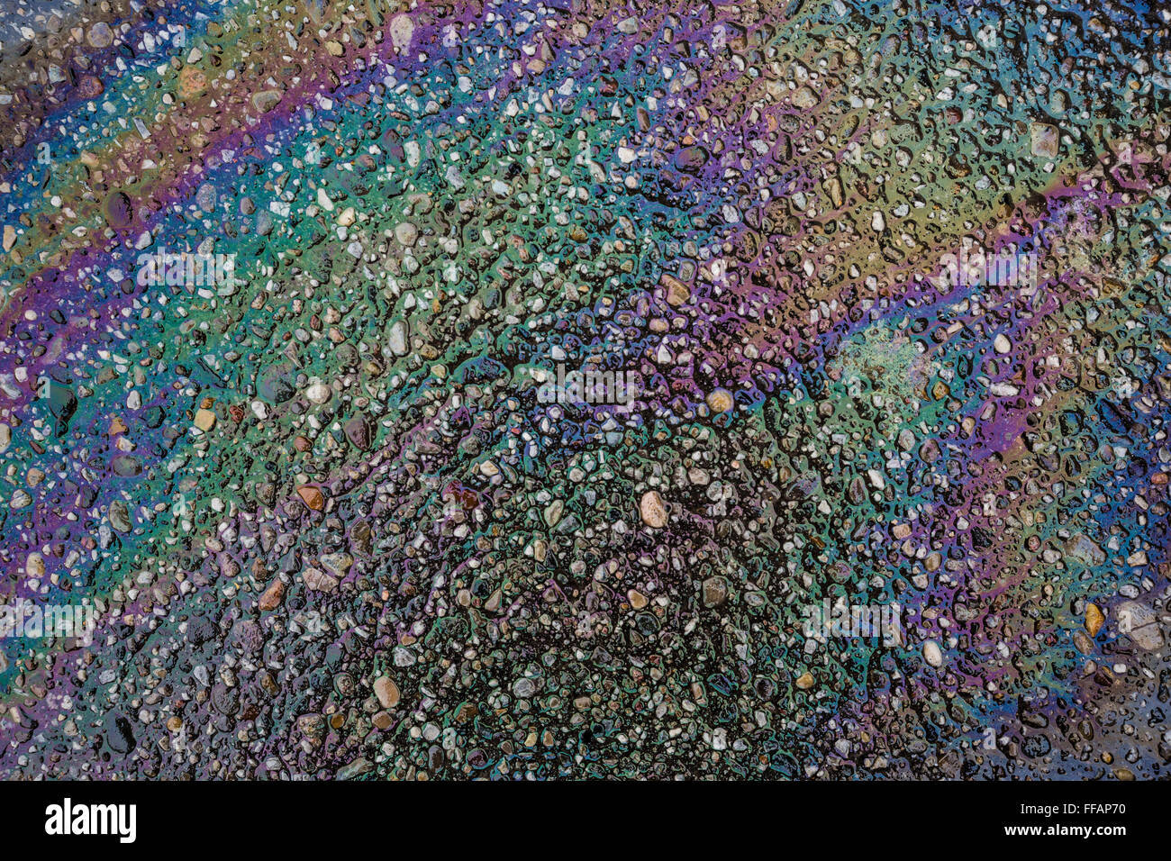 Colorful oil sheen, caused by oil leaking from a vehicle, on wet ...