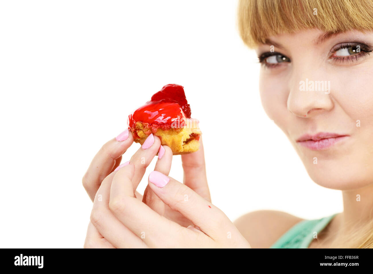 Woman holds cake cupcake in hand taking a huge bite out of dessert ...