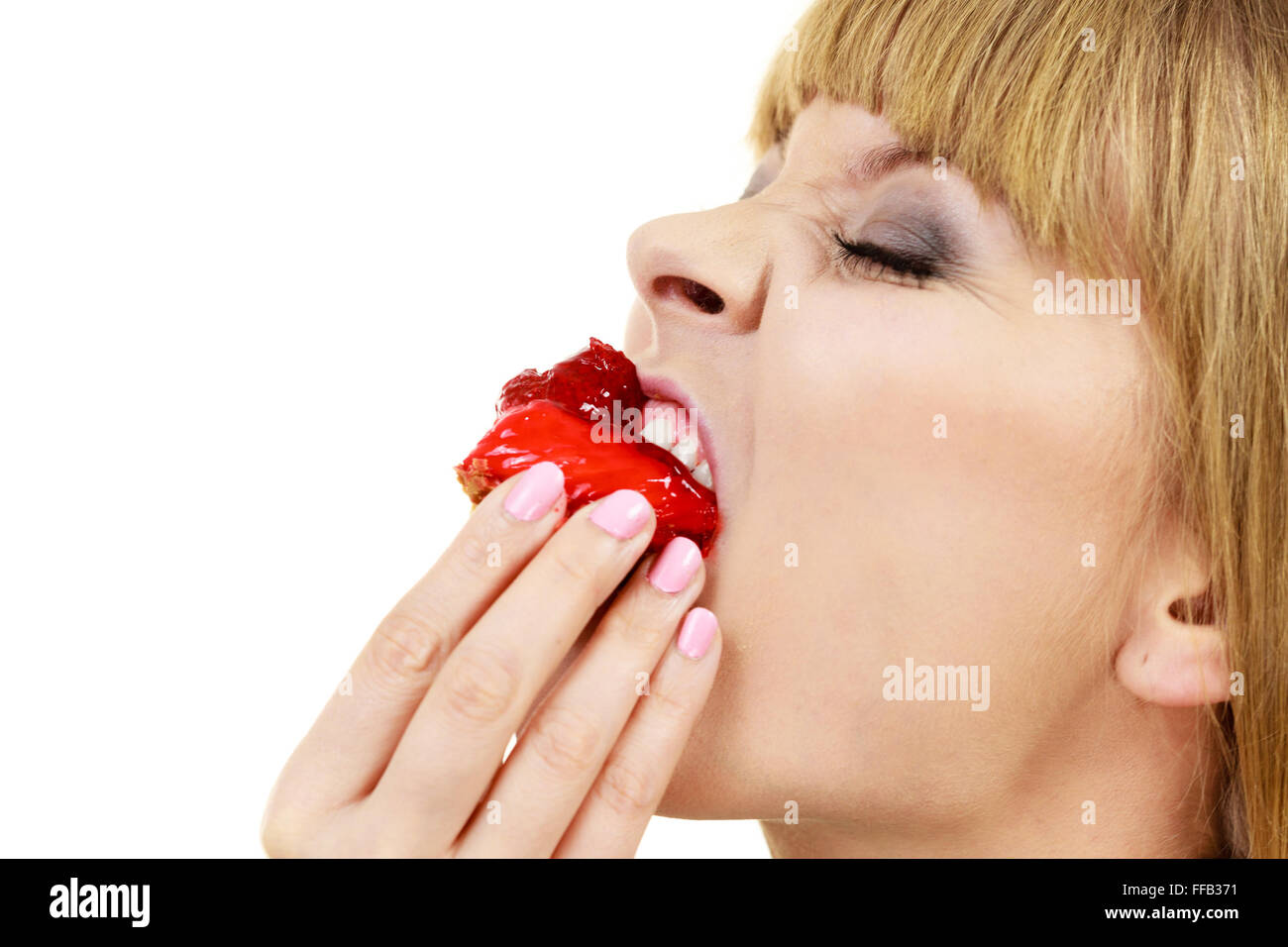 Woman holds cake cupcake in hand taking a huge bite out of dessert ...