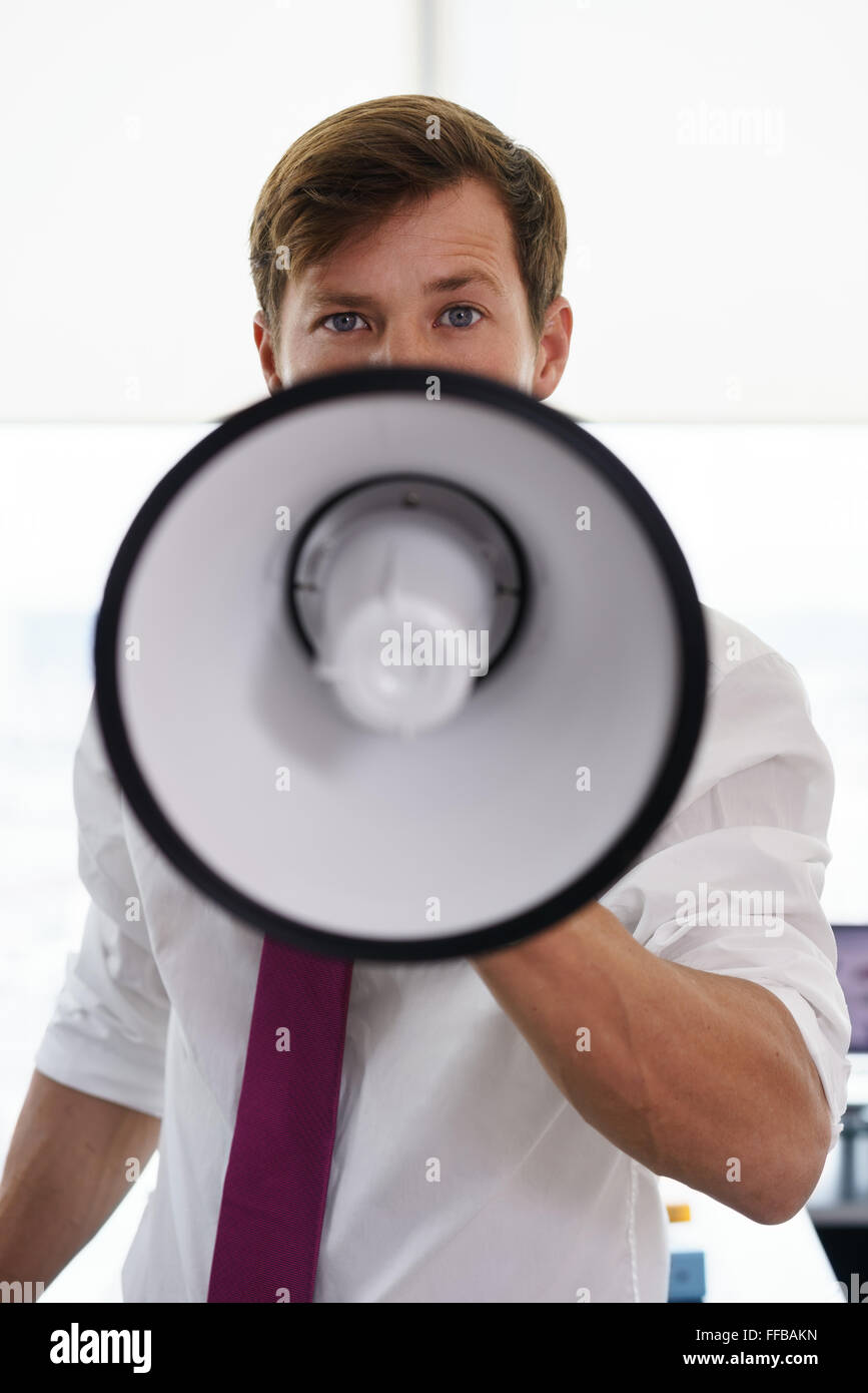 Young executive office worker holding megaphone and speaking at camera ...
