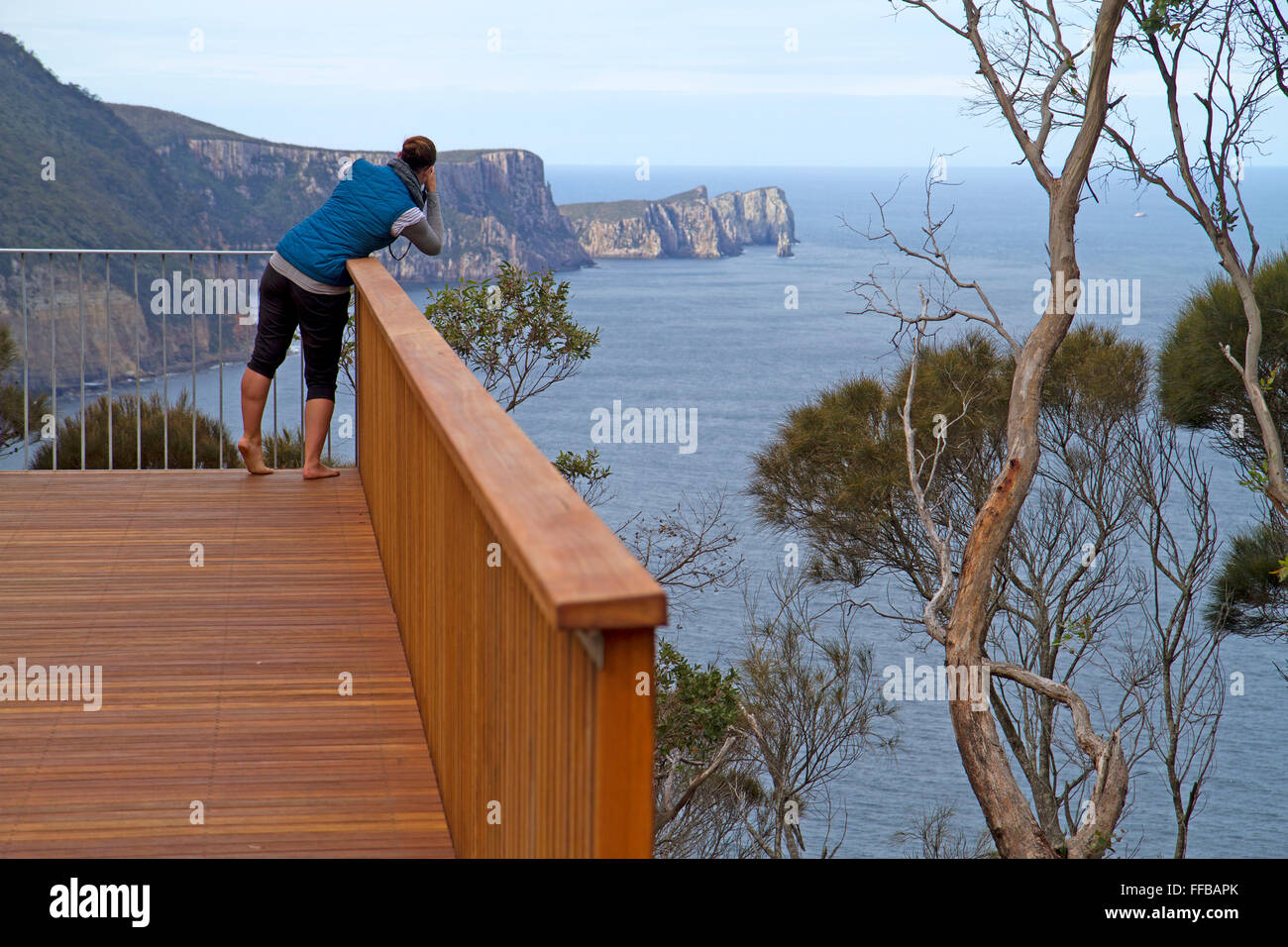 Hiker photographing Cape Hauy from the deck at Munro hut on the Three ...
