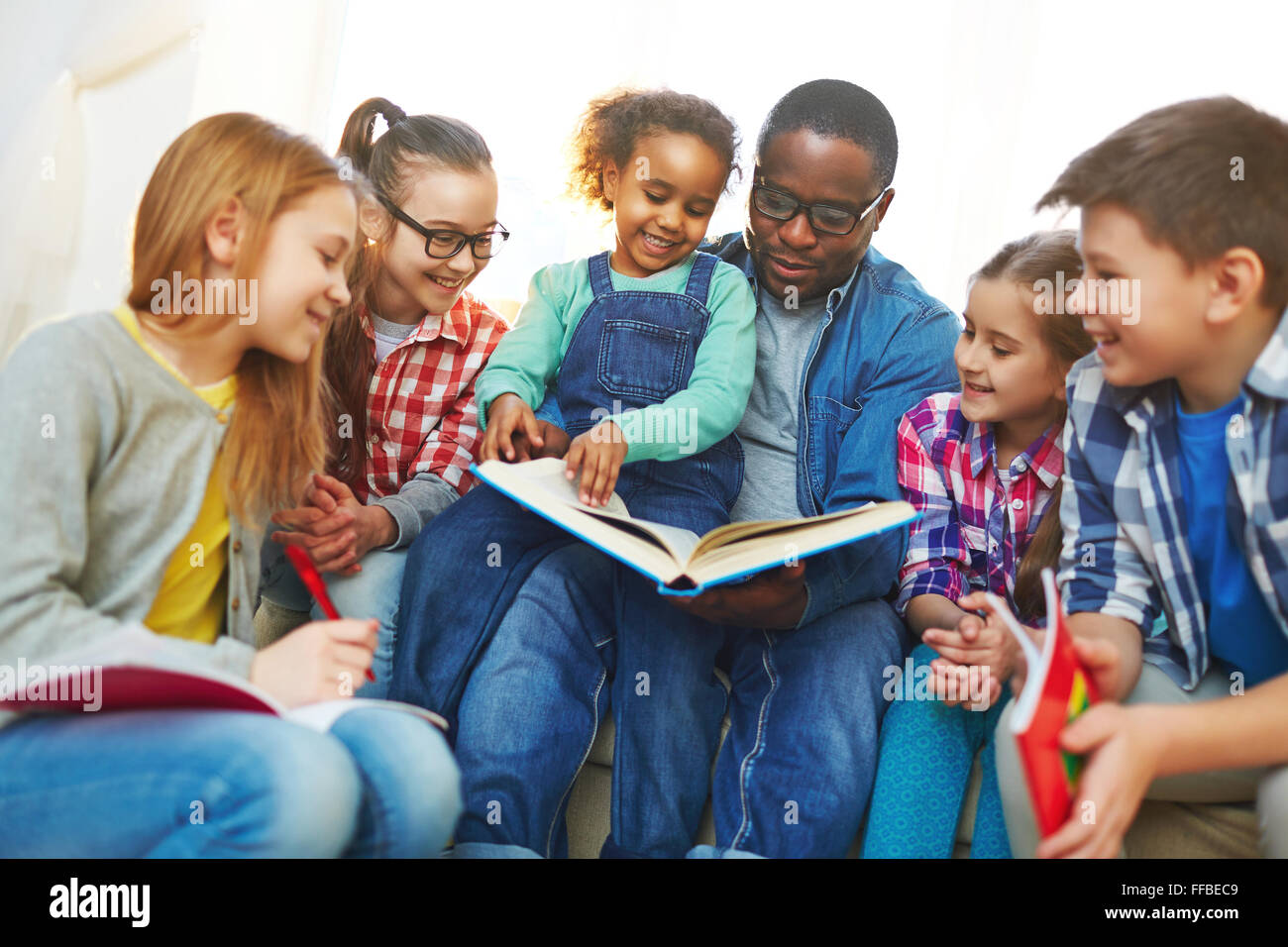Little pupils and their teacher reading book together Stock Photo - Alamy