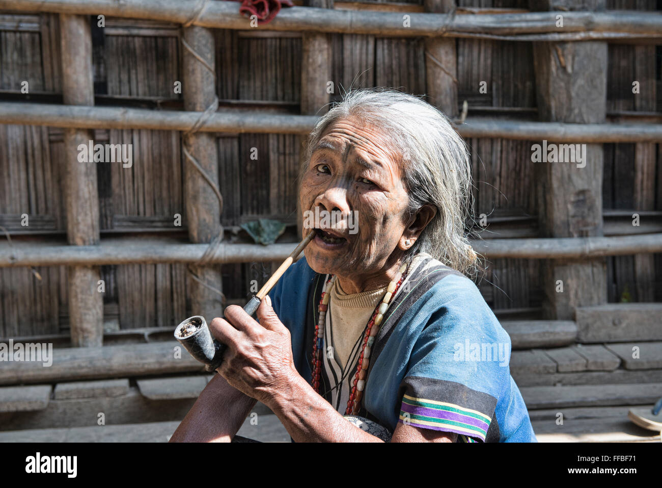 A Muun Chin woman with face tattoos smoking a corncob pipe, Kyar Daw ...