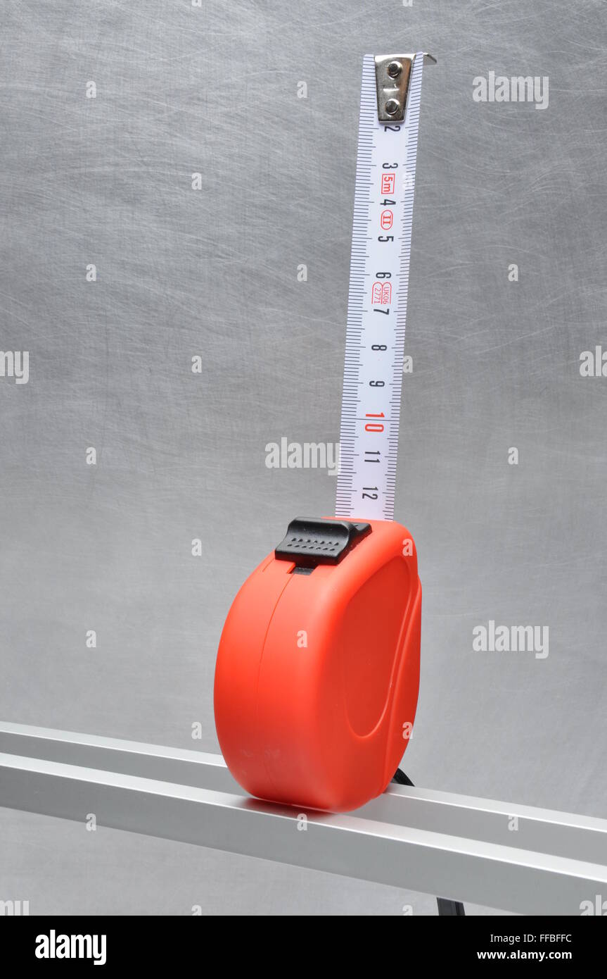 Single red tape measure on grey metal background Stock Photo - Alamy