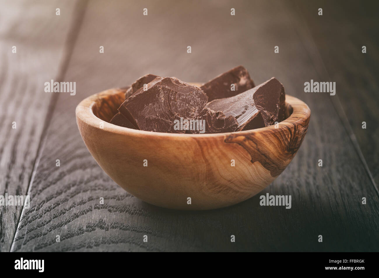 dark chocolate chunks in wooden bowl on table Stock Photo - Alamy