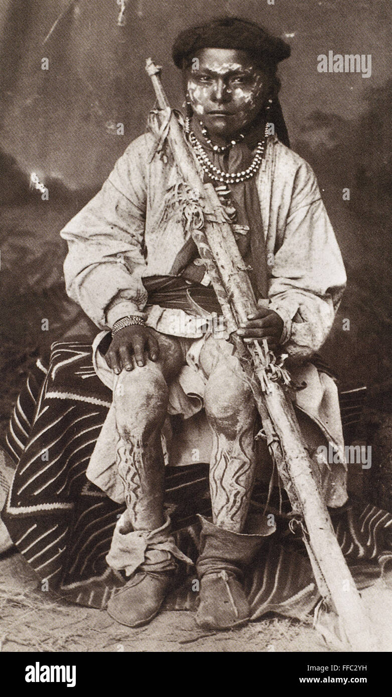COMANCHE WARRIOR. /nA young Comanche warrior holds a rifle in a fringed ...