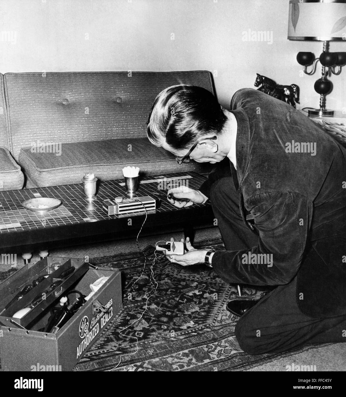WIRETAPPING. /nA man installing an electronic listening device in a ...
