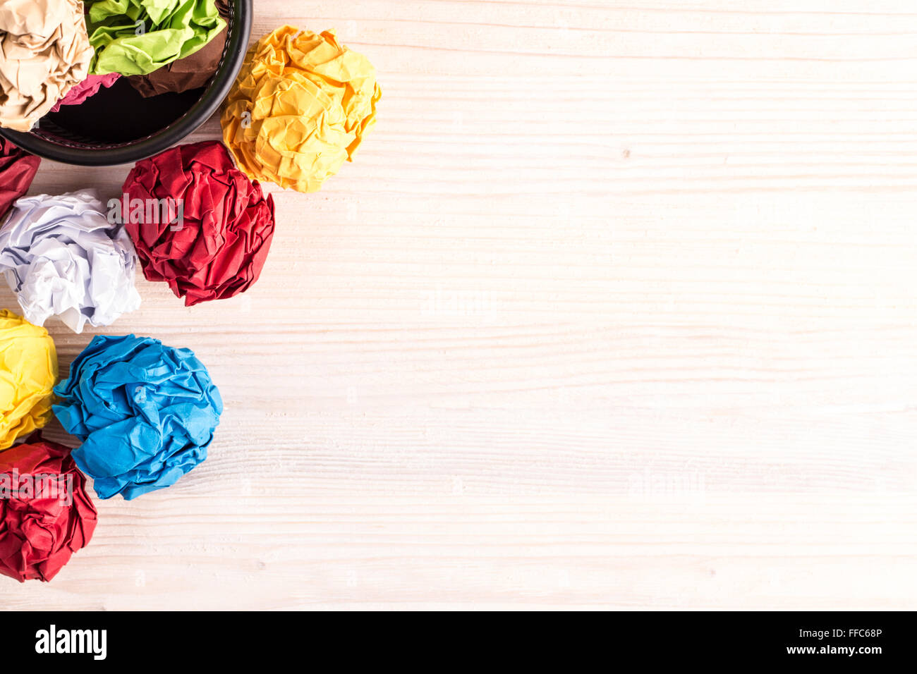 Creased color papers and office bin on light wooden table Stock Photo ...