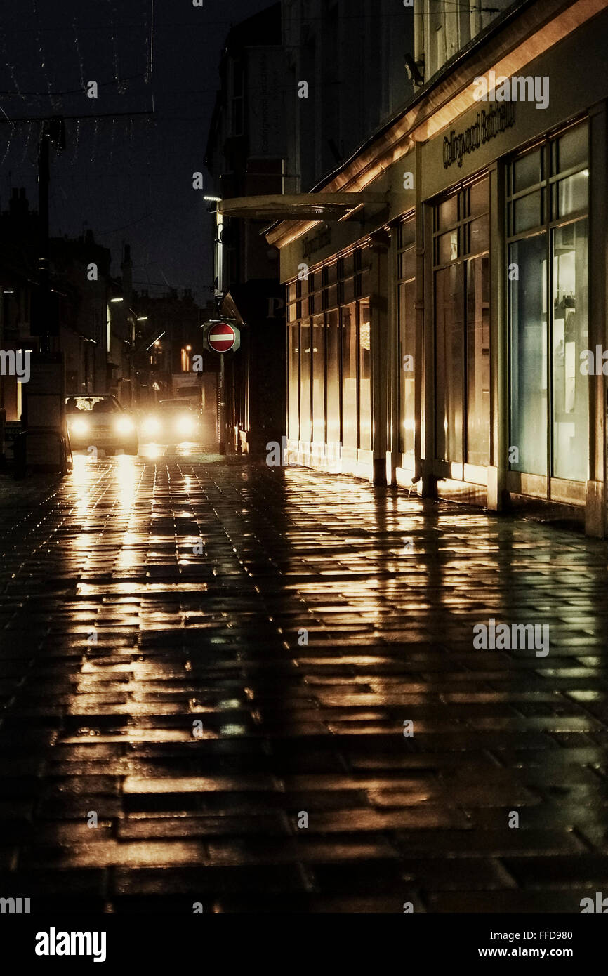 Wet Weather: Car headlights reflect on wet pavements and shop windows ...