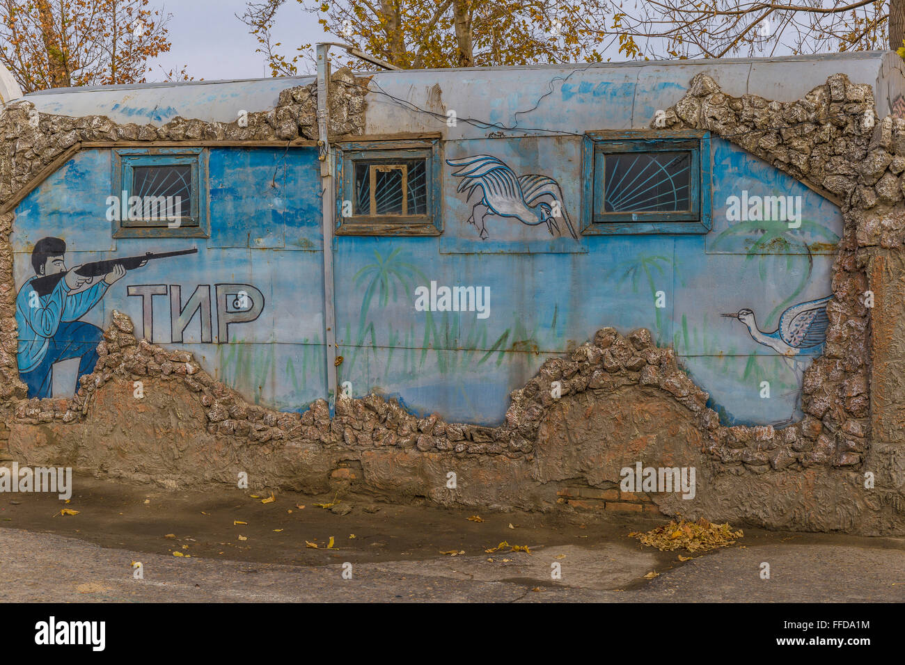 A strange mural outside Bukhara Zoo showing a man wi a rifle shooting ...