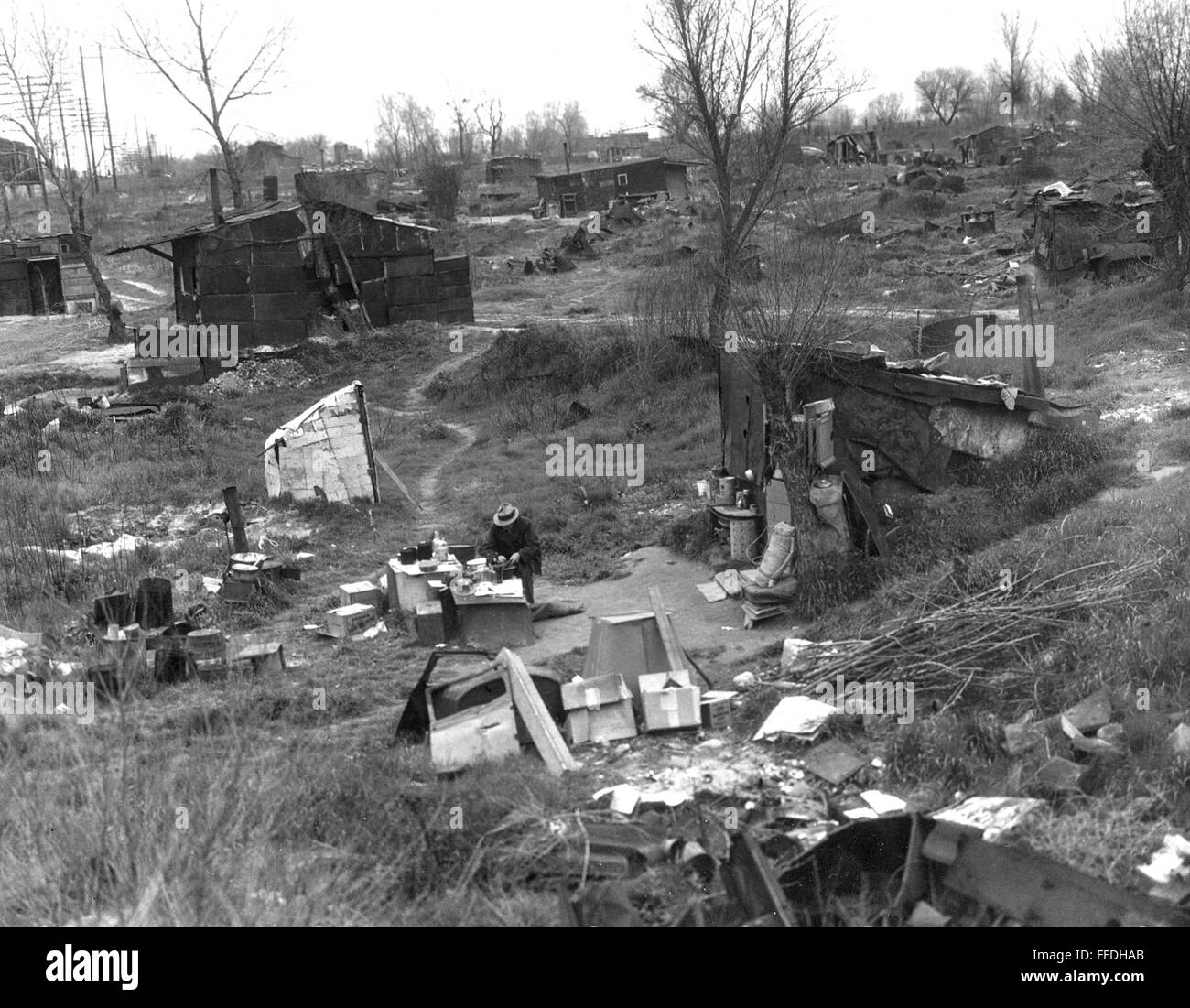 MIGRANT LABOR CAMP, 1935. /nA man preparing a meal in a run down camp ...