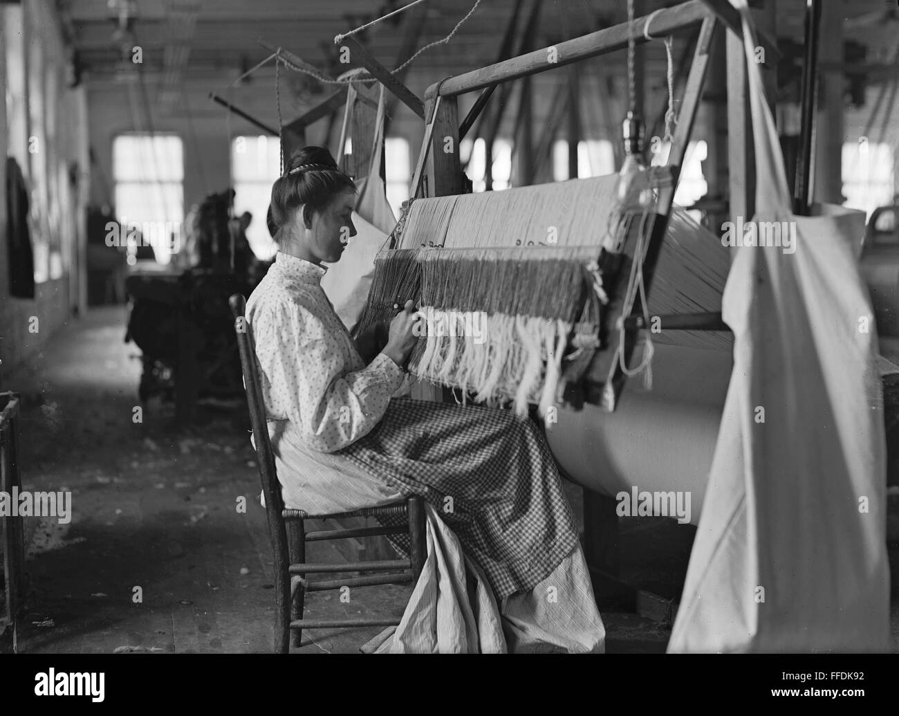 HINE: CHILD LABOR, 1908. /nA girl working at a beam warper in a textile ...