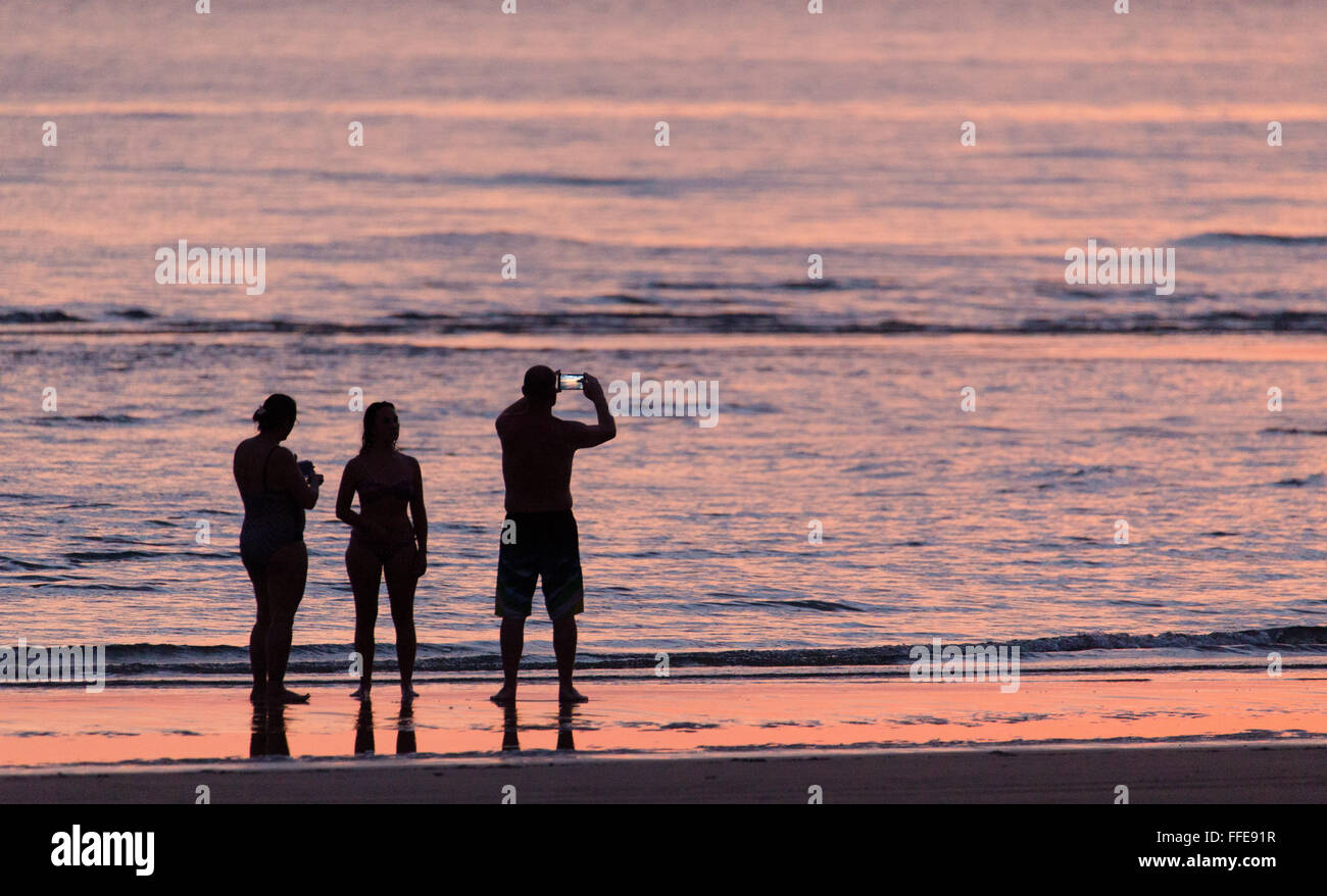 Silhouette of three people at sunset off a beach in Sabah, Malaysia ...