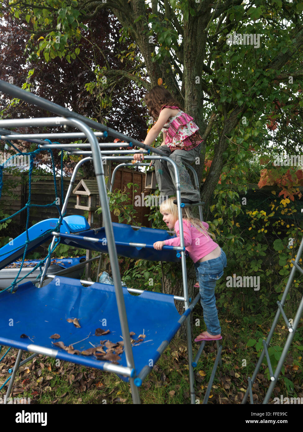 Two Girls Sisters On Climbing Frame In Garden England Stock Photo - Alamy