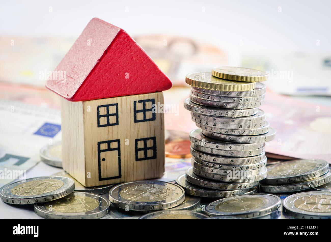 wooden toy house, banknotes and pile of coins Stock Photo - Alamy