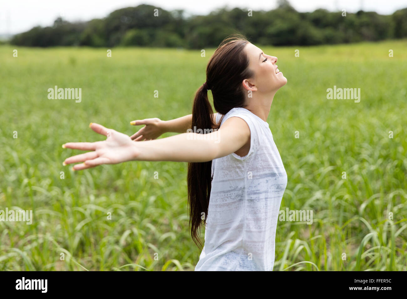 side view of smiling teen girl with arms open on grassland Stock Photo ...