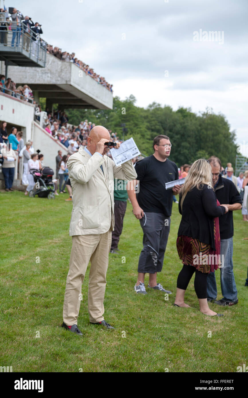 Spectator with binoculars watching horses racing at Corlay Racecourse ...