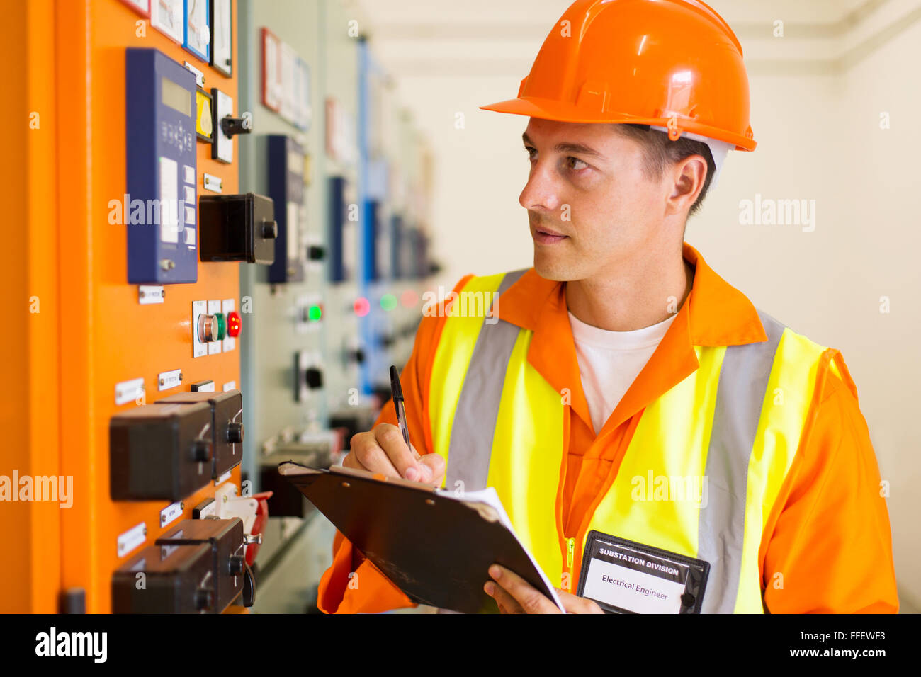 handsome electrical engineer taking machine readings in control room ...