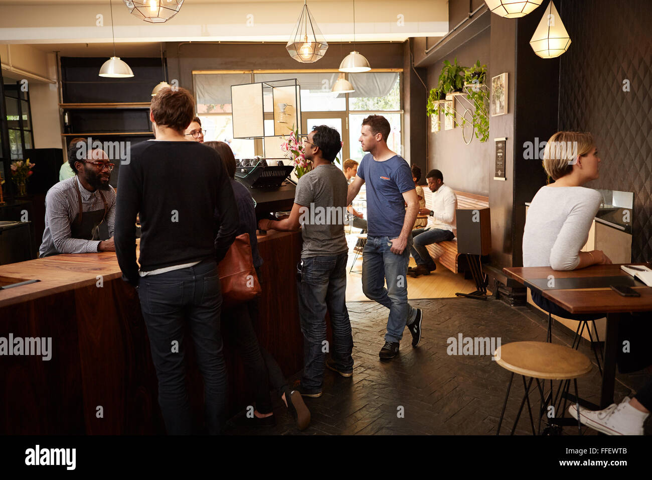 May people standing on either side of the counter in a modern coffee ...