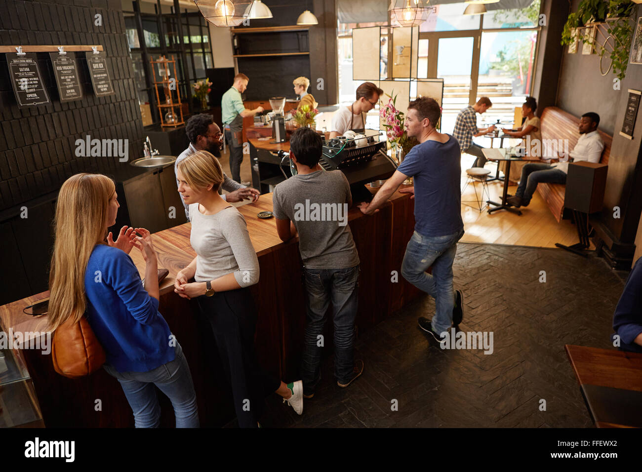 Women and men waiting at a modern coffee shop wooden counter talking ...