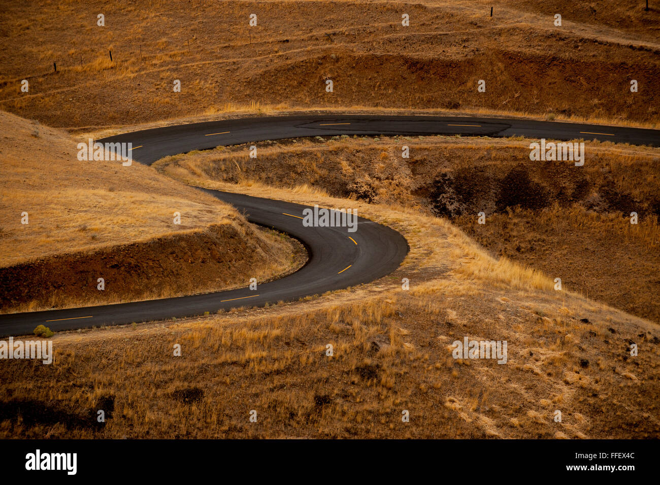 A curving two lane asphalt roadway winds through the hills of eastern ...