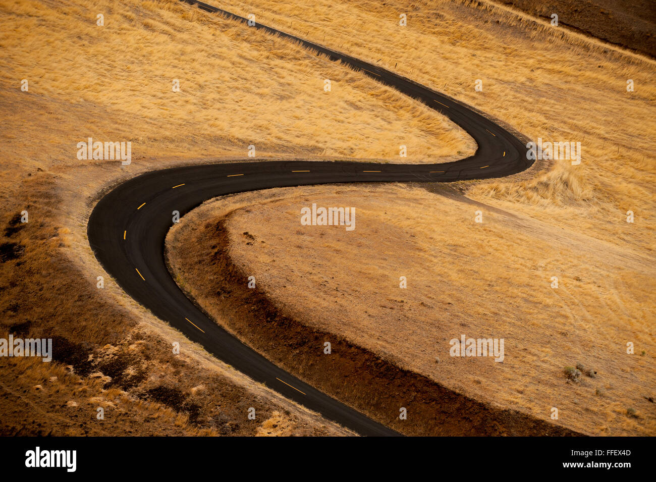 A curving two lane asphalt roadway winds through the hills of eastern ...