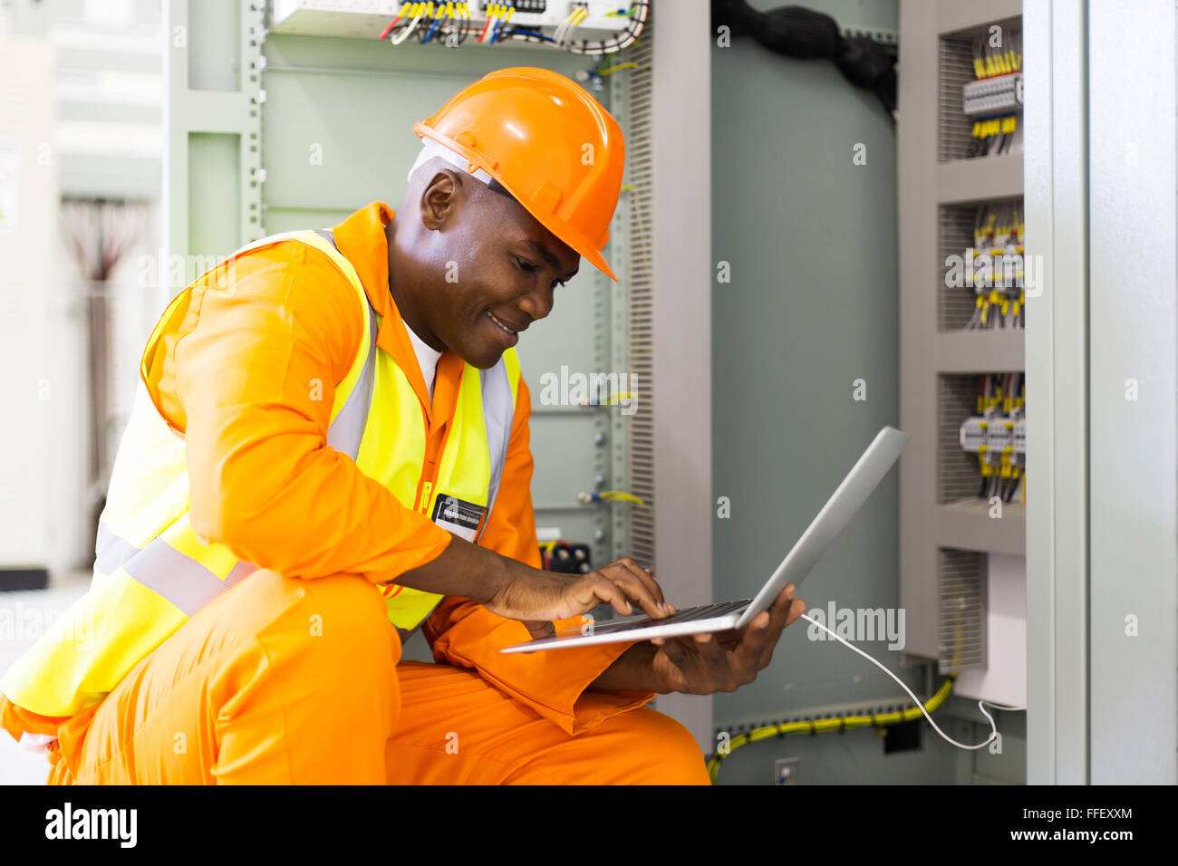 young African American engineer using laptop in machine control room ...