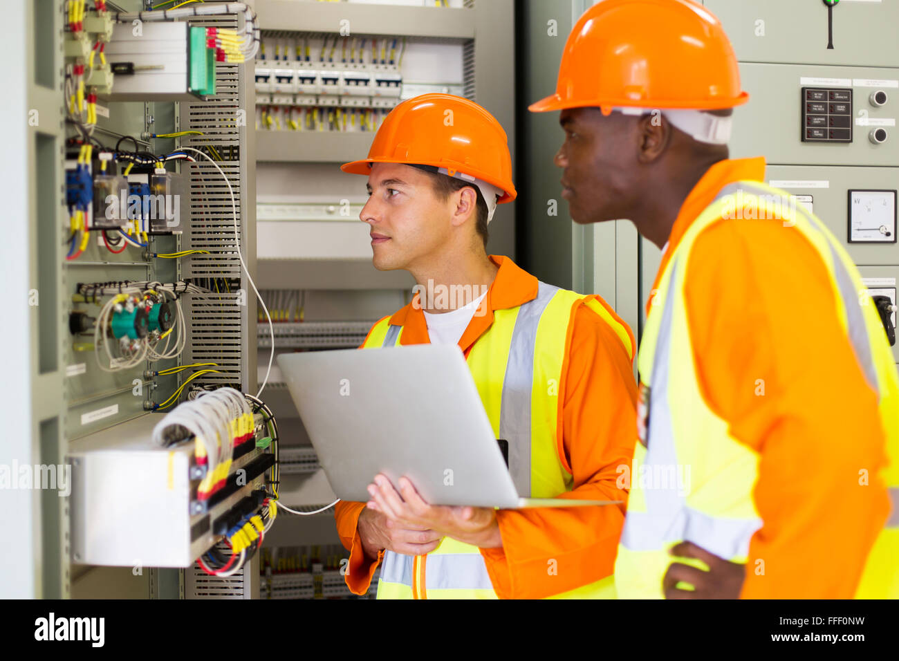 experienced multiracial industrial technicians checking transformer ...