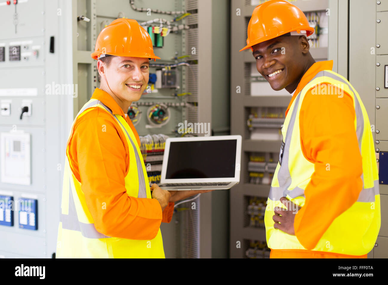 happy electrical co-workers using laptop computer checking transformer ...