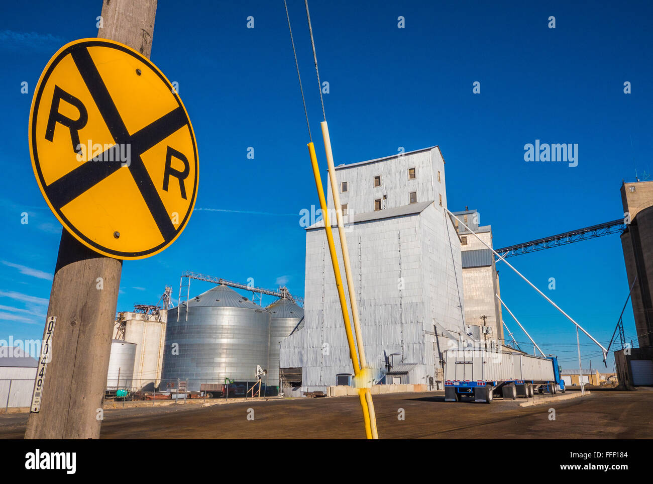 A railroad crossing warning sign stands outside a grain elevator yard ...