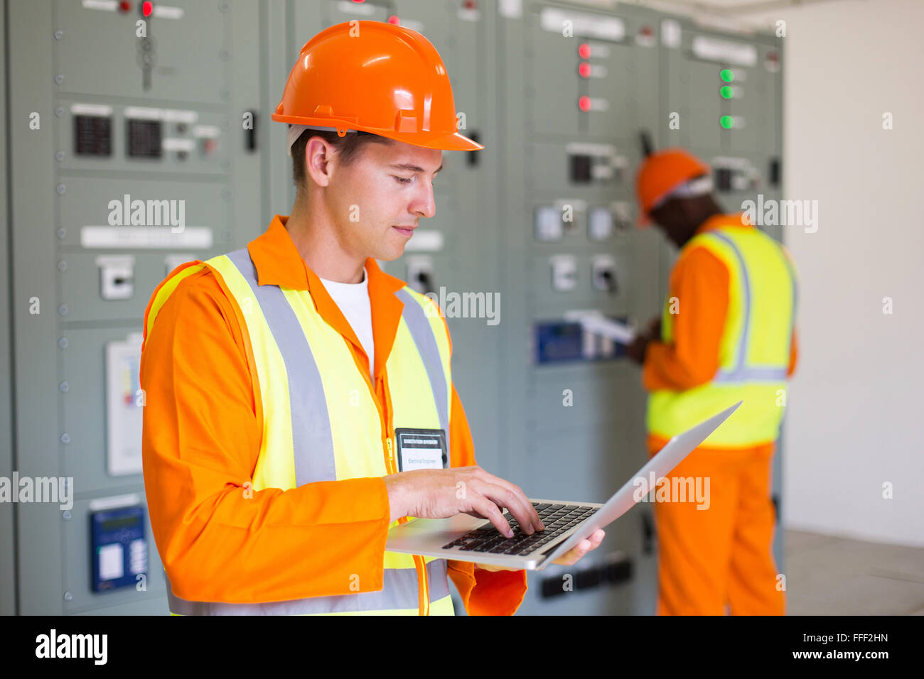 electrical worker working on laptop with colleague on background Stock ...