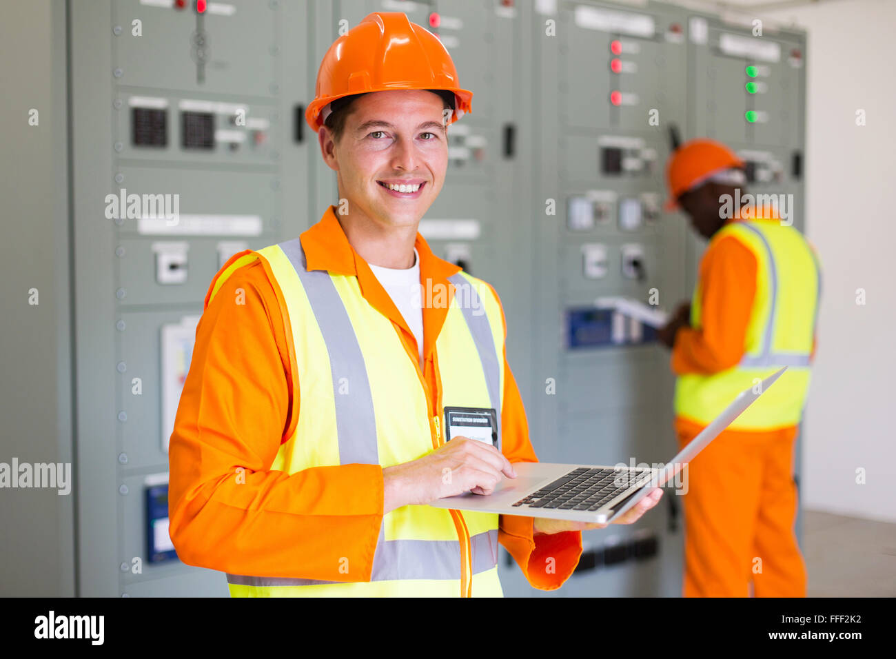 happy electrical technician using laptop in power plant control room ...