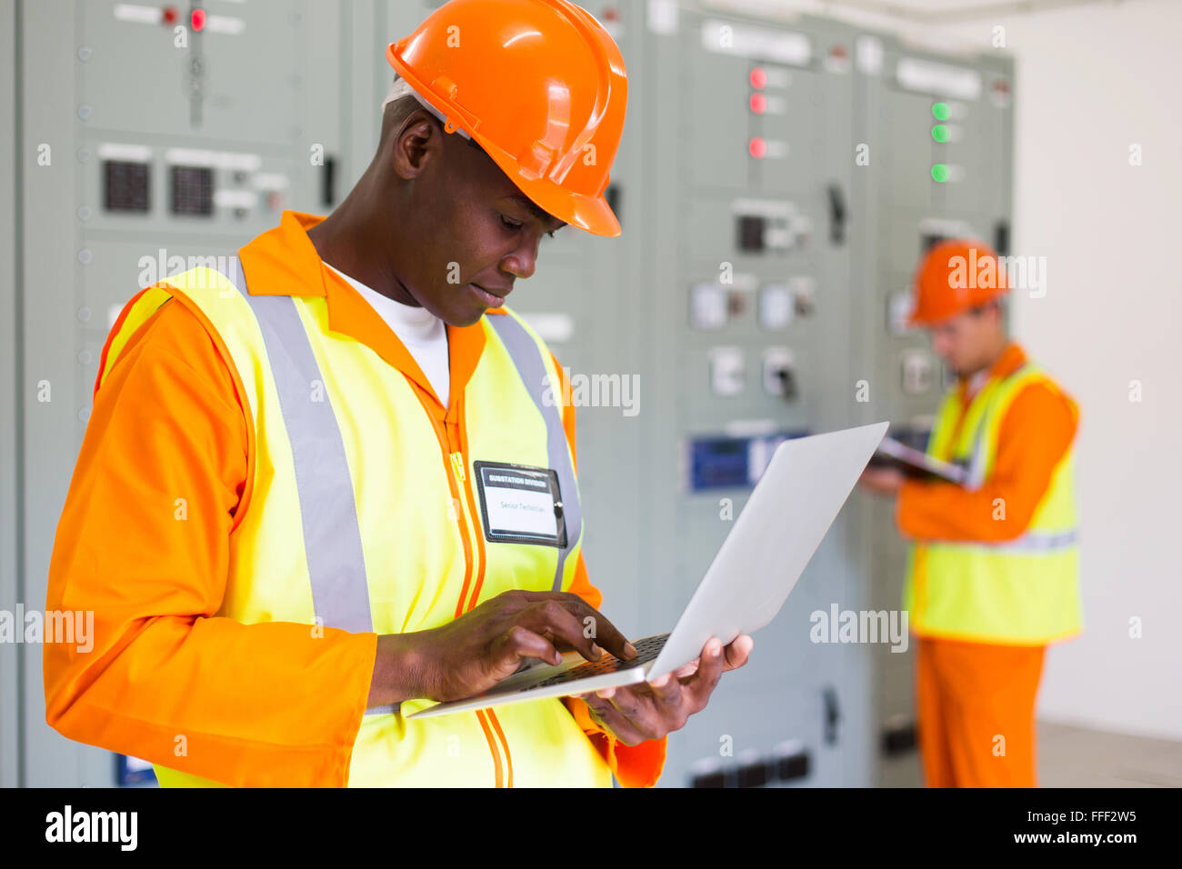 black technical worker using laptop with colleague on background Stock ...